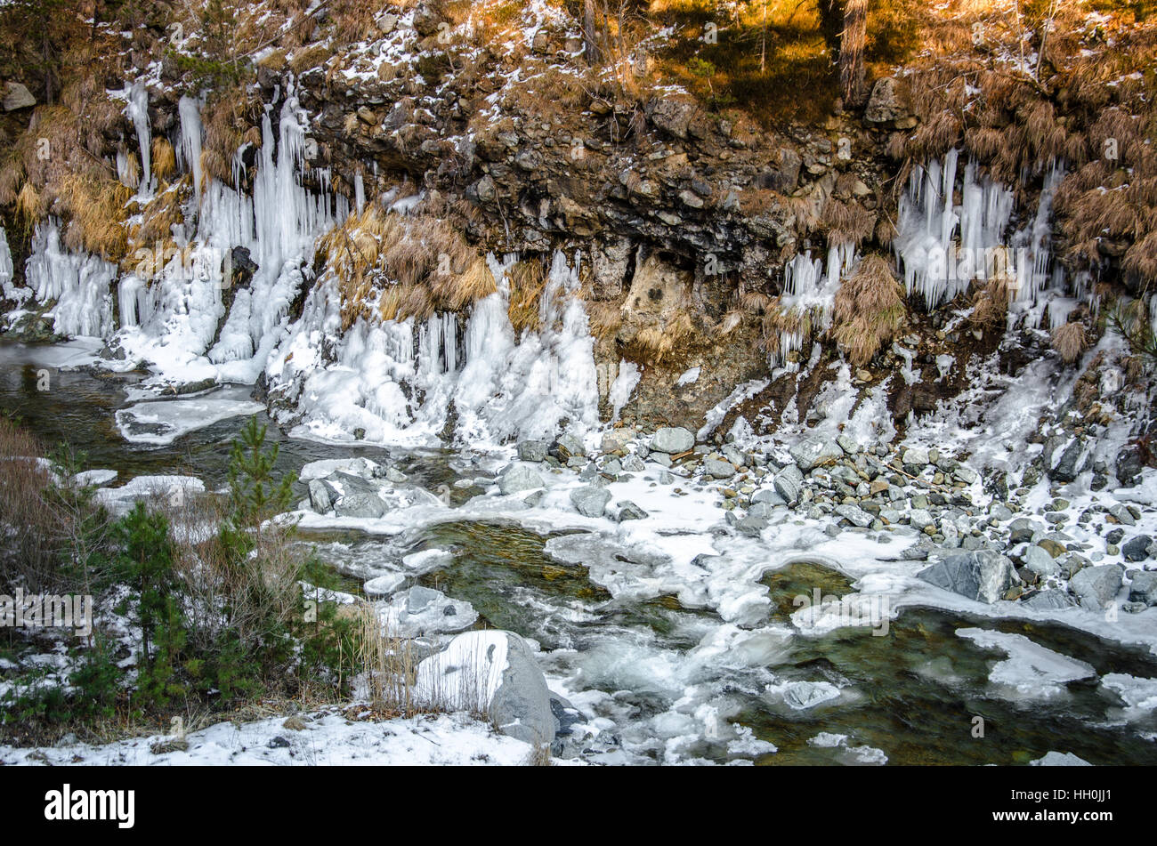 Frozen waterfall stalactites, icicles in a forest over a river, Pindus ...