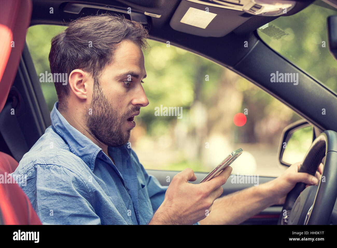 Man sitting in car with mobile phone texting while driving. Distracted ...