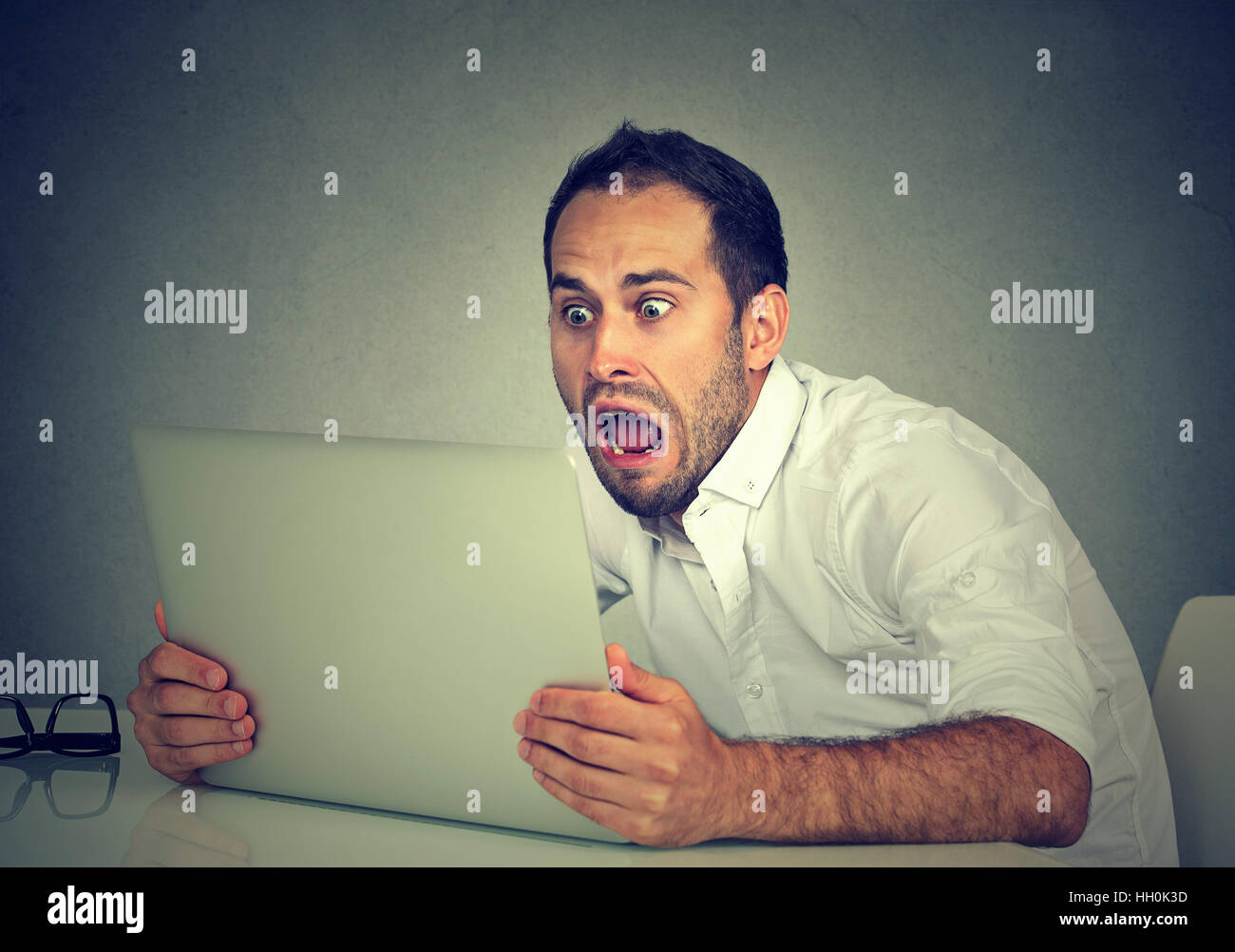 Portrait young shocked man with laptop computer sitting at table Stock ...