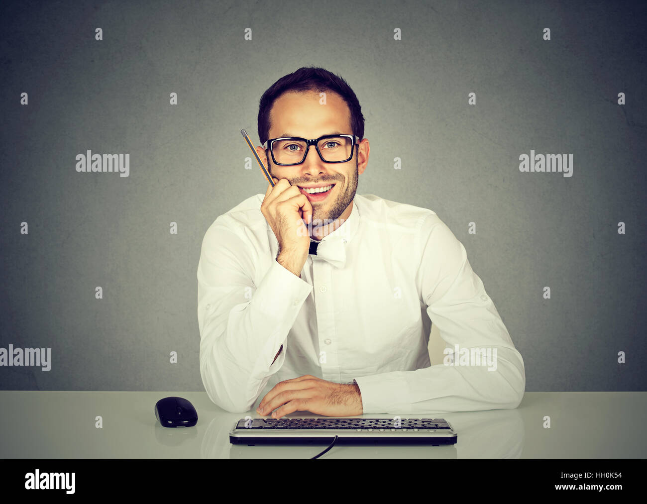 Smiling young handsome man sitting in front of computer keyboard Stock ...