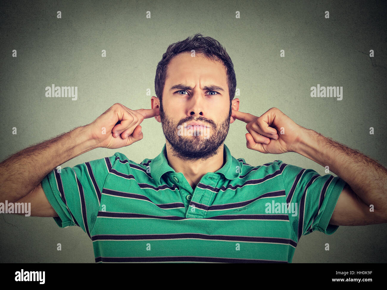 headshot displeased young man plugging ears with fingers doesn't want ...