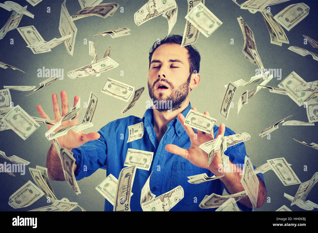 Young entrepreneur business man with eyes closed trying to catch dollar ...