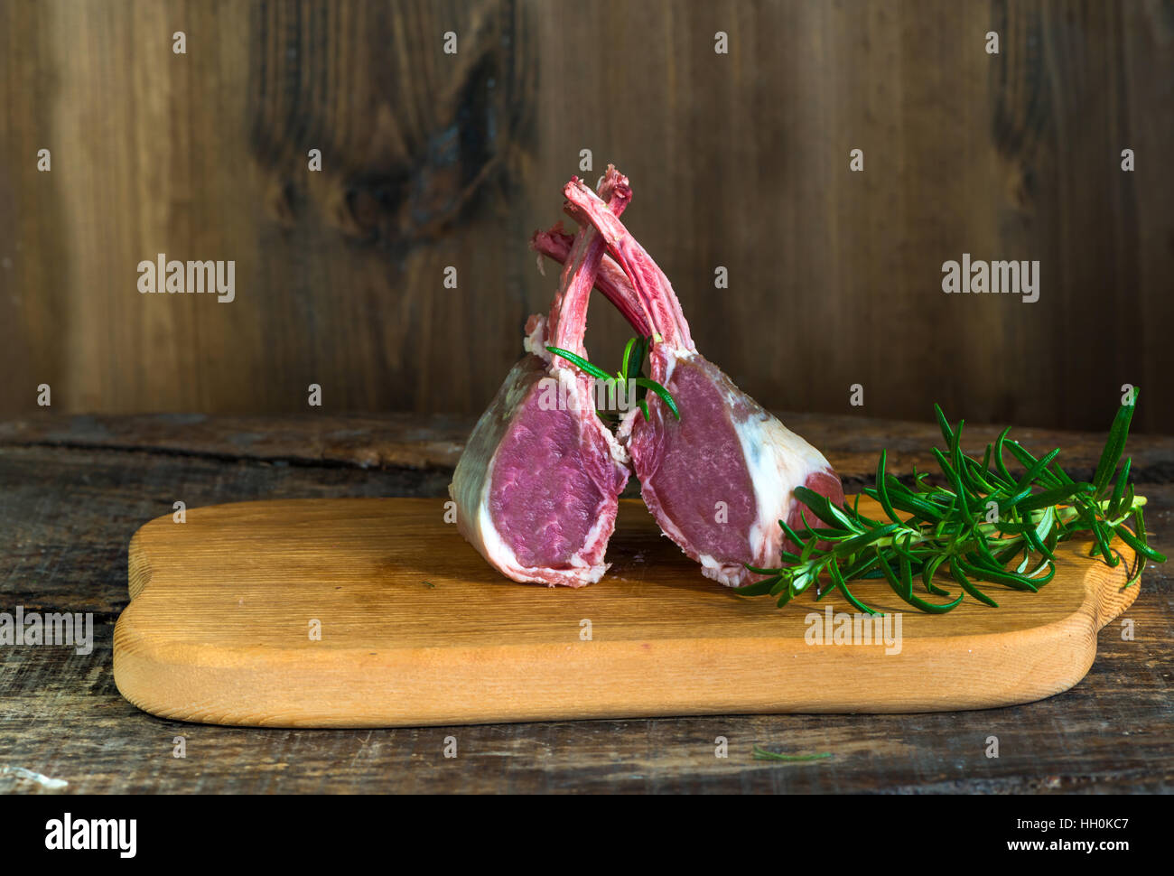 Uncooked rack of lamb with rosemary on wooden background Stock Photo ...