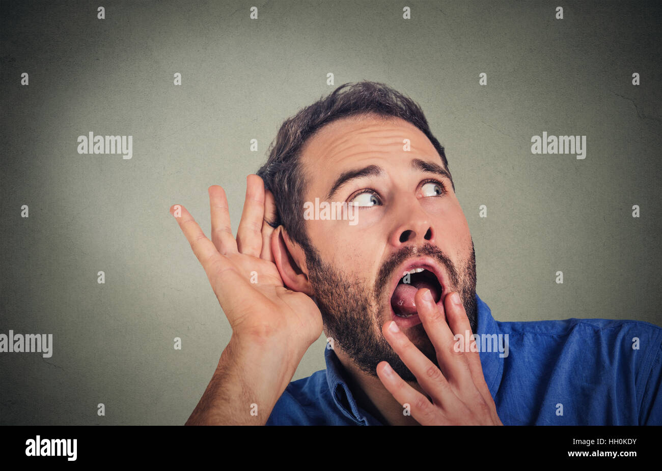 handsome, young, nosy, shocked man hand to ear gesture, carefully ...