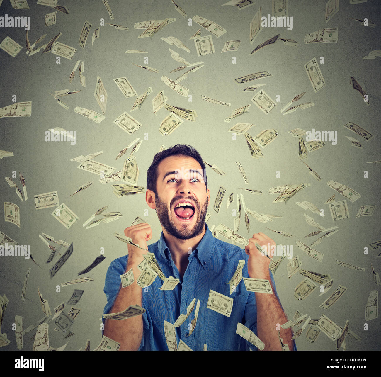 happy man exults pumping fists celebrates success screaming under money ...