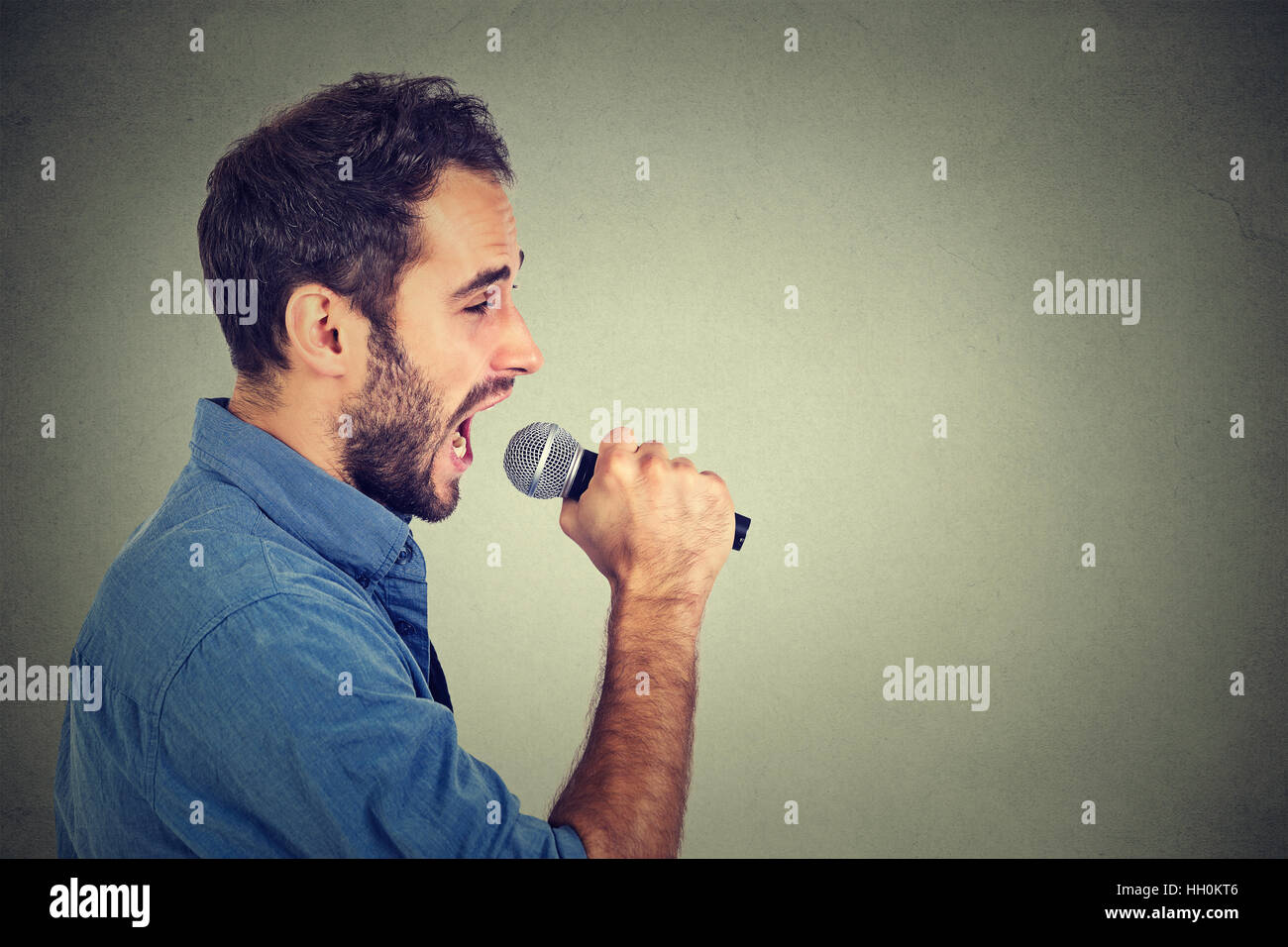 Singing man isolated on gray wall background Stock Photo - Alamy