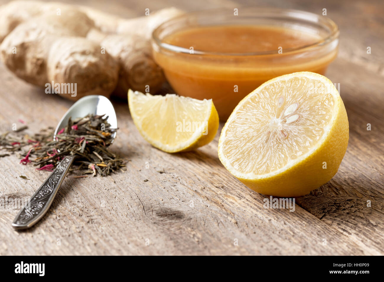 lemon, tea leaves, ginger and honey bowl on the old wooden background ...