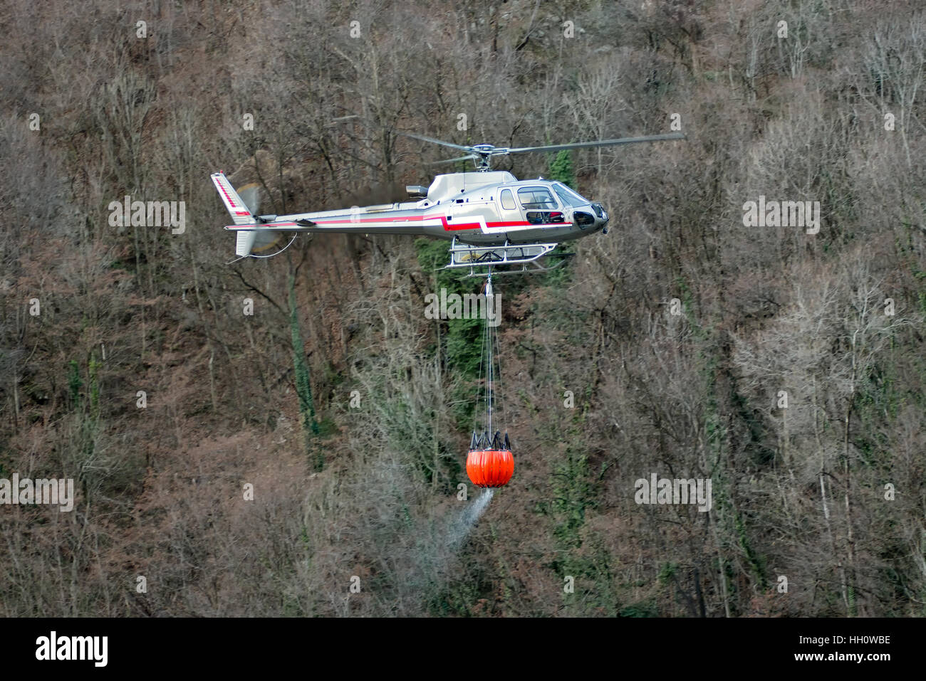 Helicopter transporting a bucket full of water suspended below the ...