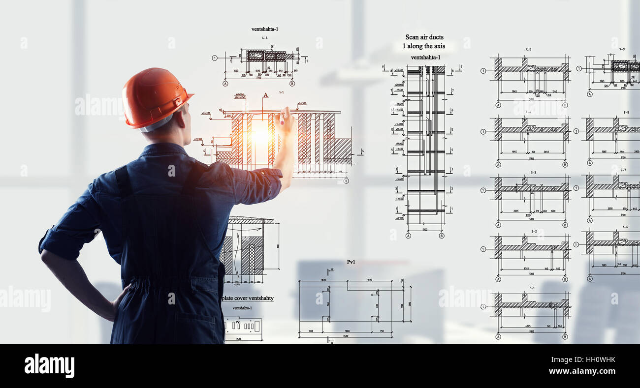 Rear view of engineer man in helmet and overall sketching construction ...