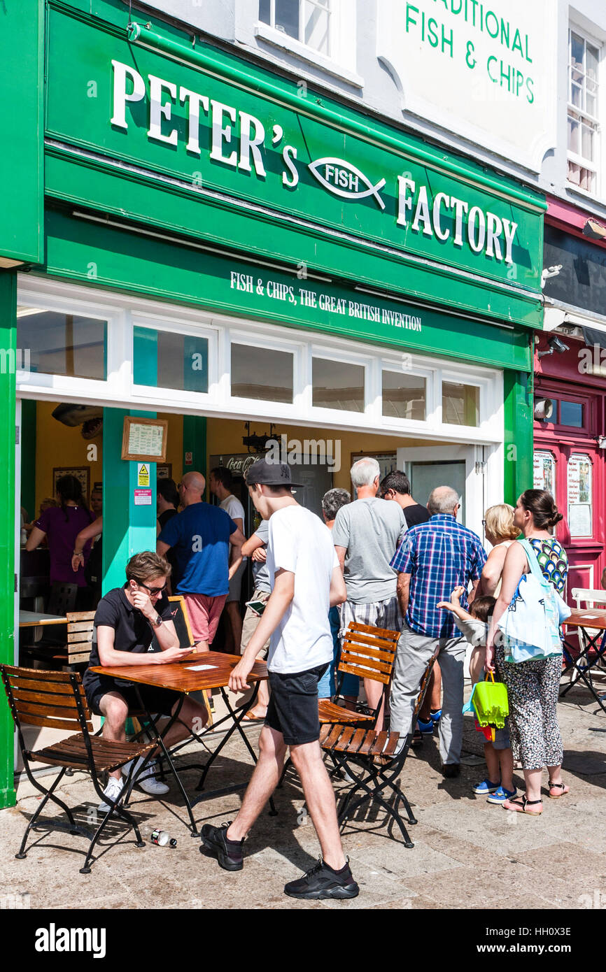 Long mid-day queue of people for fish and chip shop on seafront during ...