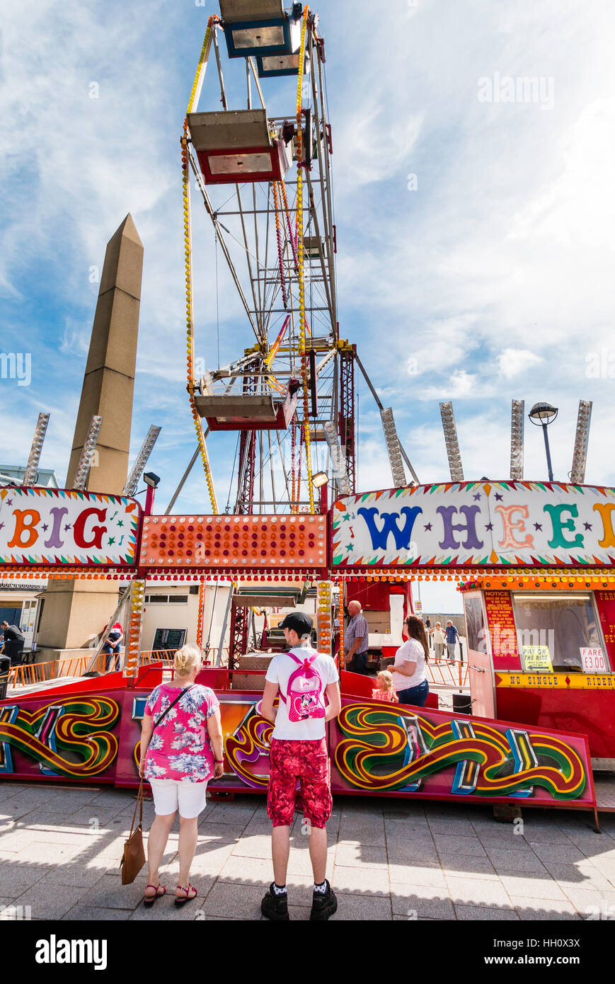 People buying tickets at booth for ferris wheel also known as big wheel ...