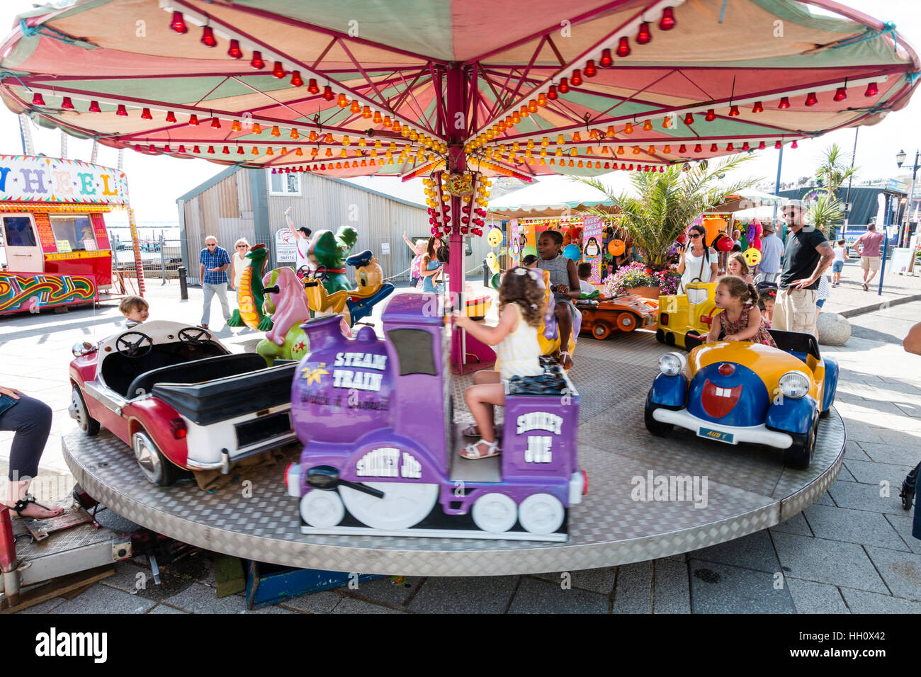 England, Ramsgate. Children enjoying small car and train carousel on ...