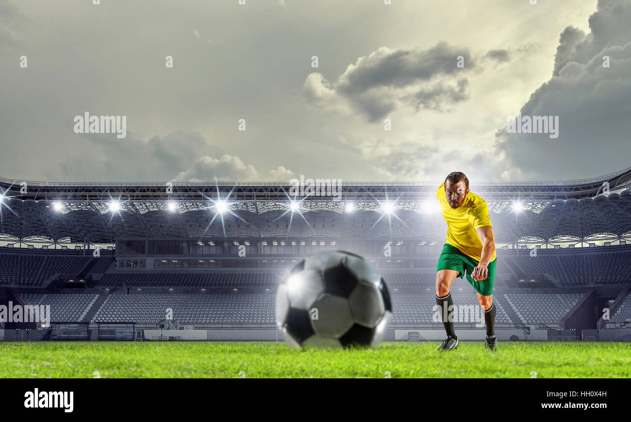 Soccer player with ball in action at stadium. Mixed media Stock Photo ...