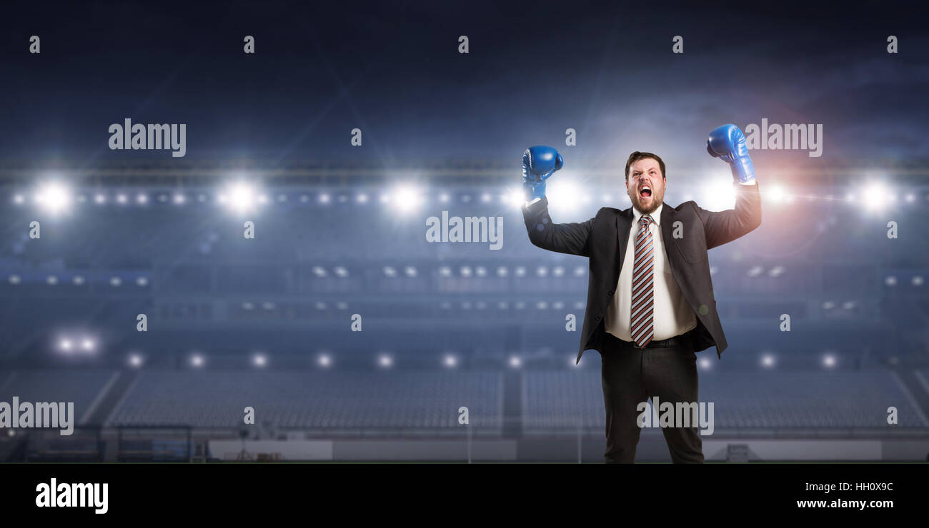 Determined businessman in blue gloves rising hands to celebrate his ...