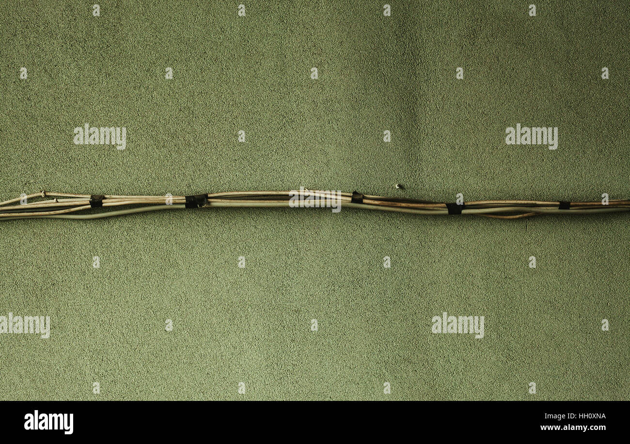 Details of a texture of an old green wall with cables in the middle ...