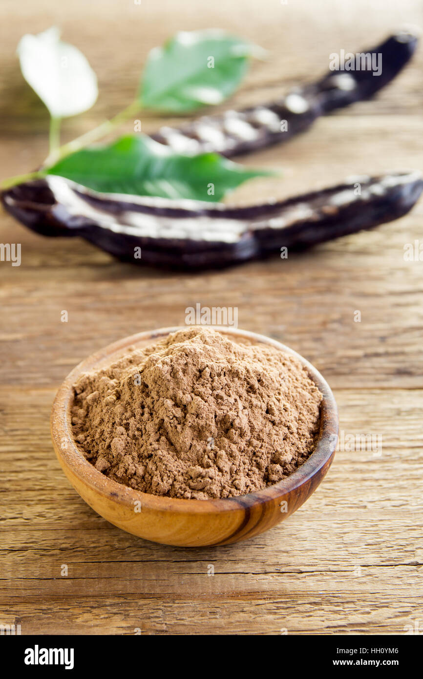 Carob pods and carob powder over wooden background with copy space ...