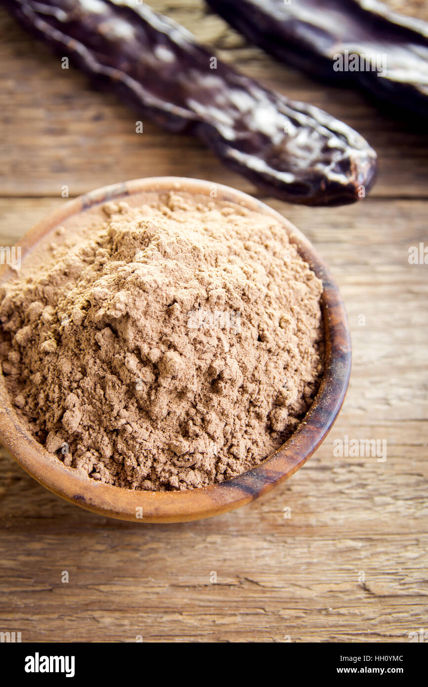 Carob pods and carob powder over wooden background with copy space ...