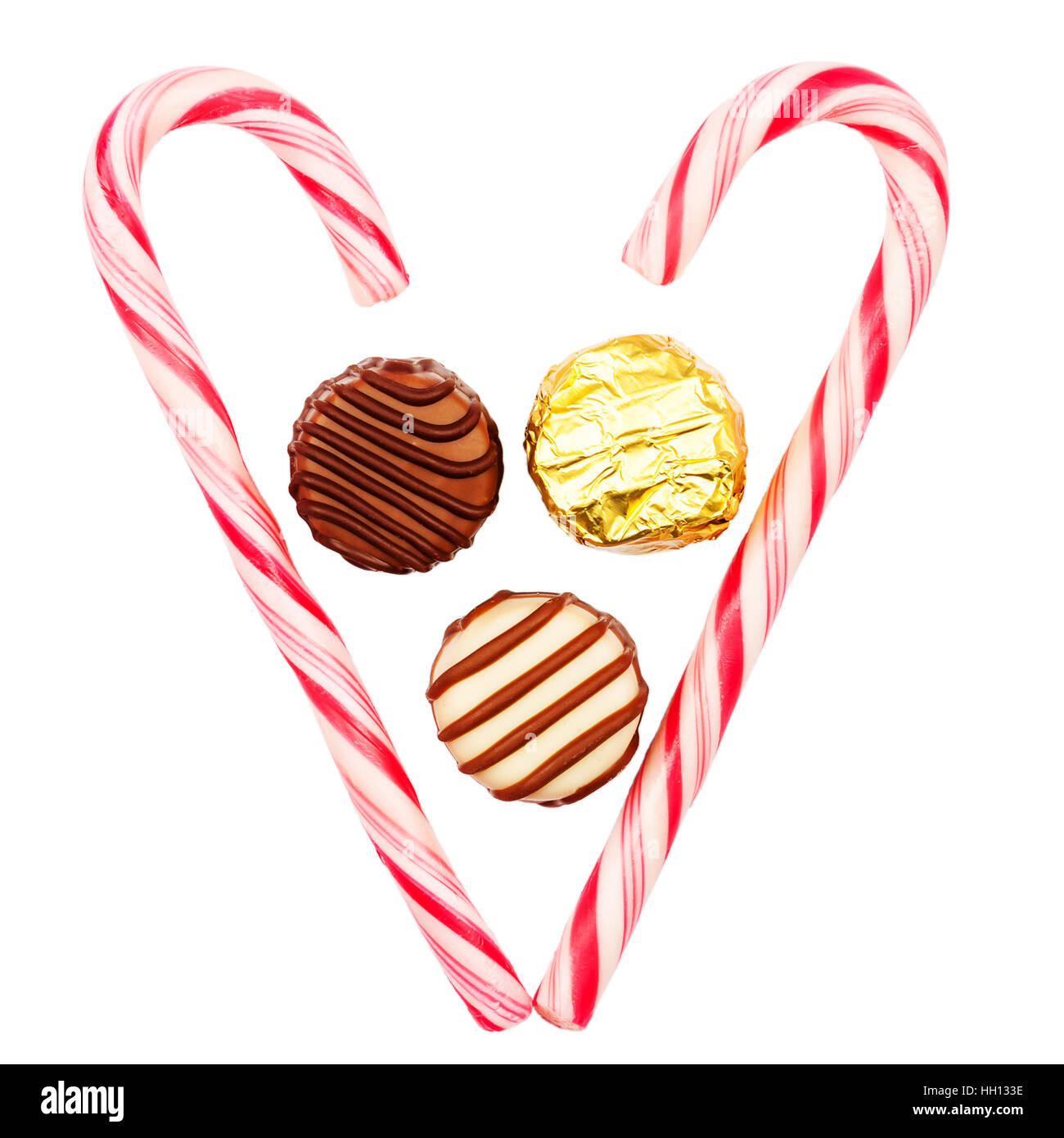Heart made of candy canes with three chocolate candies inside isolated ...