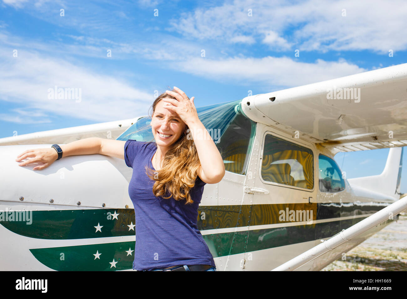 Young smiling woman standing near private plane Stock Photo - Alamy