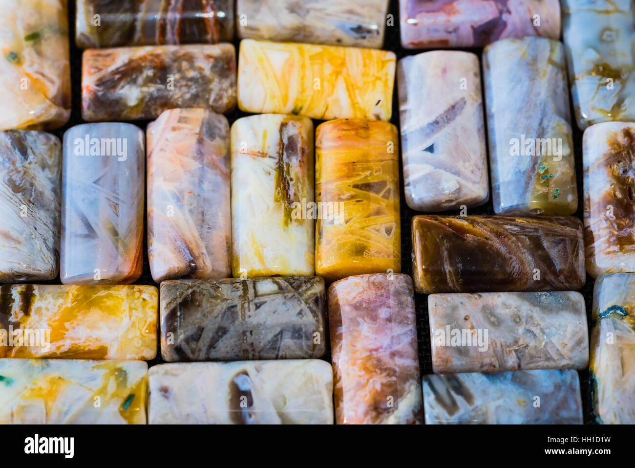 Collection of shiny rectangular agate beads background on black weave ...