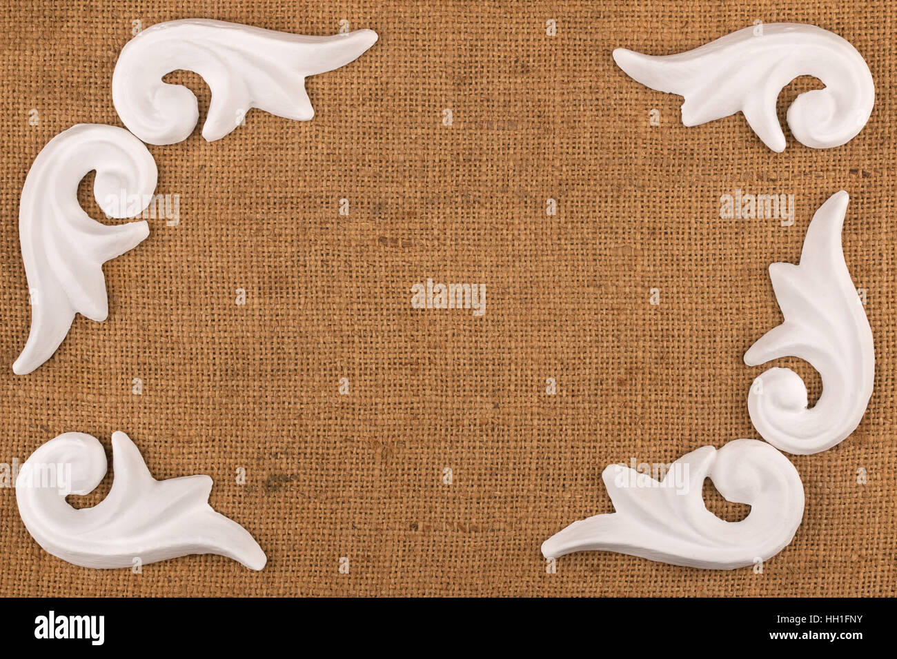 Luxury frame made of white stucco plaster lying on burlap. With space ...