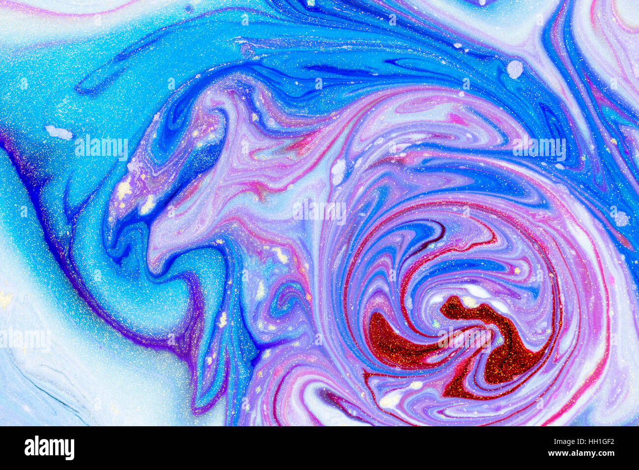 Colorful inks with glitter swirled in white liquid creates abstract ...