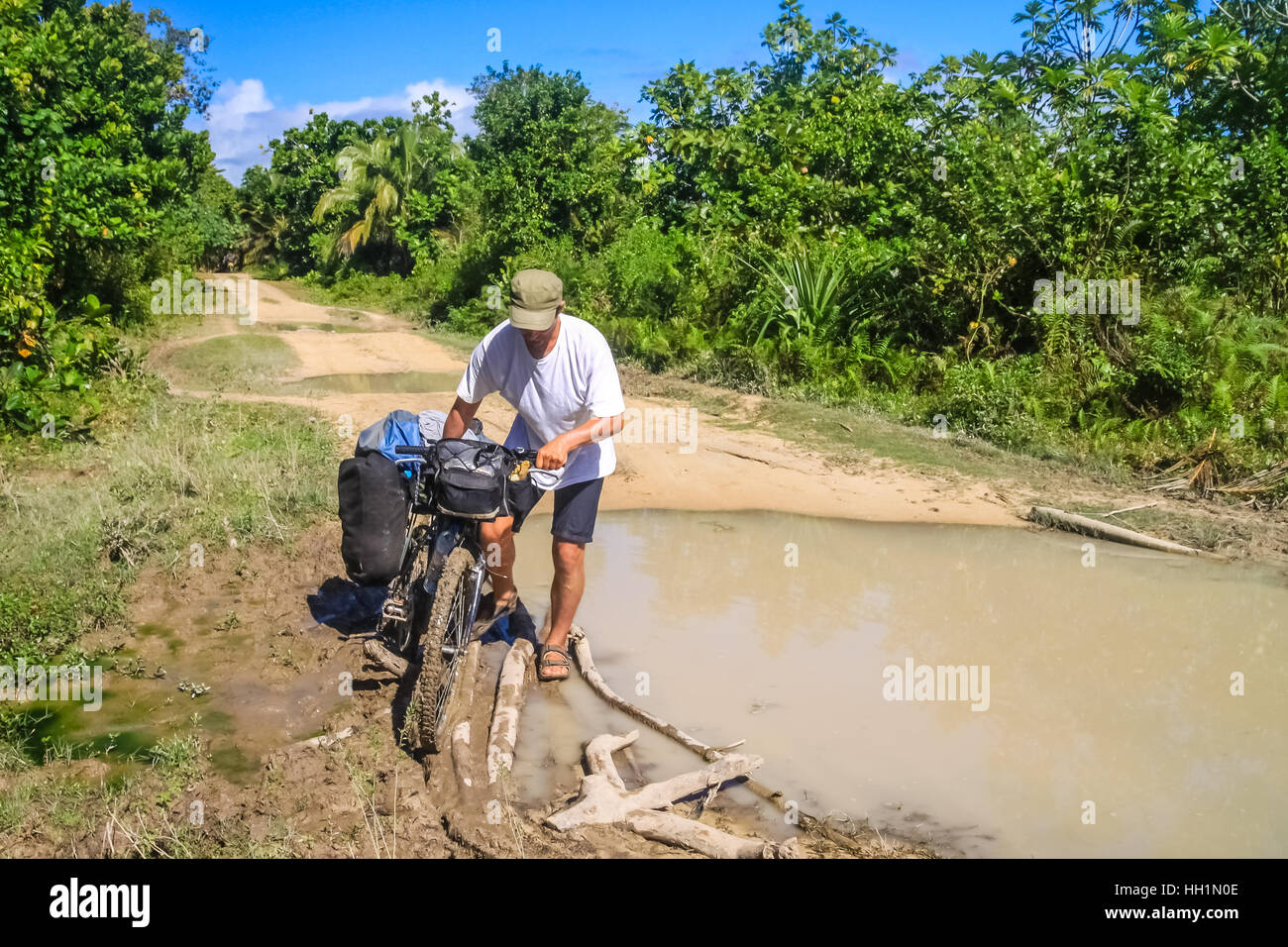 Cyclist struggling with bicycle on difficult jungle track towards ...