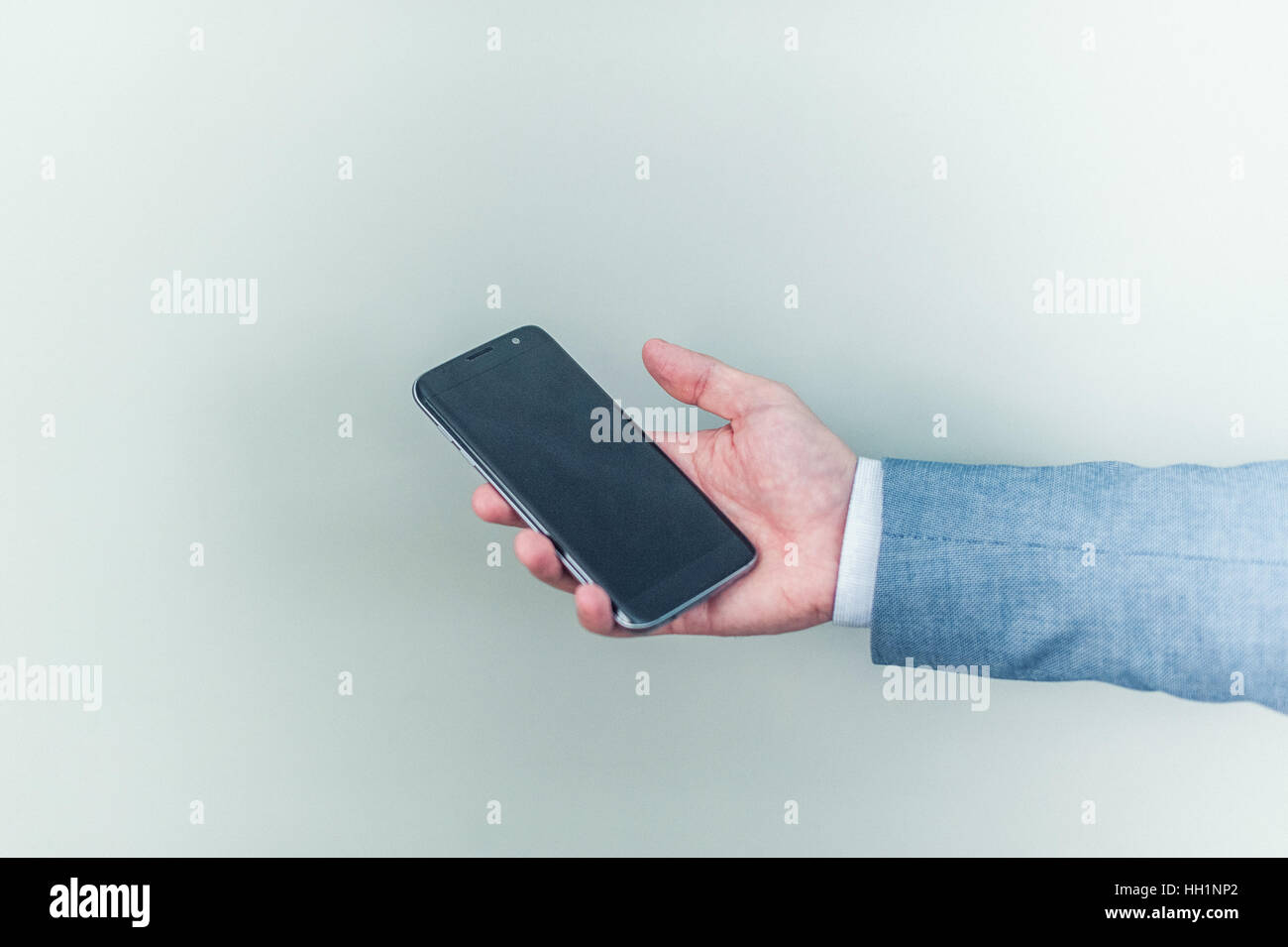 New shiny phone in male hands on a gray background Stock Photo - Alamy