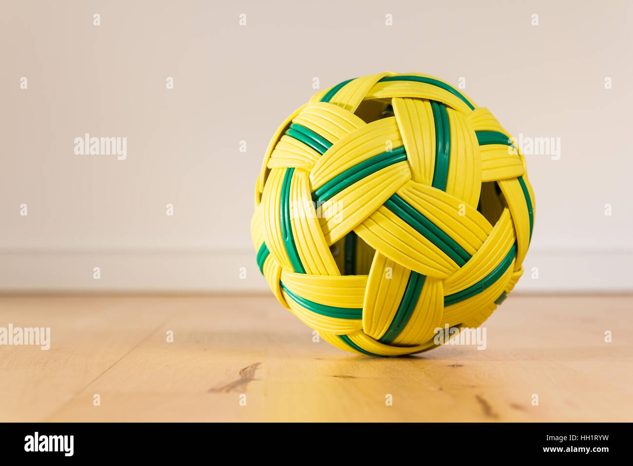 Green and yellow rattan ball lying on a wooden floor Stock Photo - Alamy