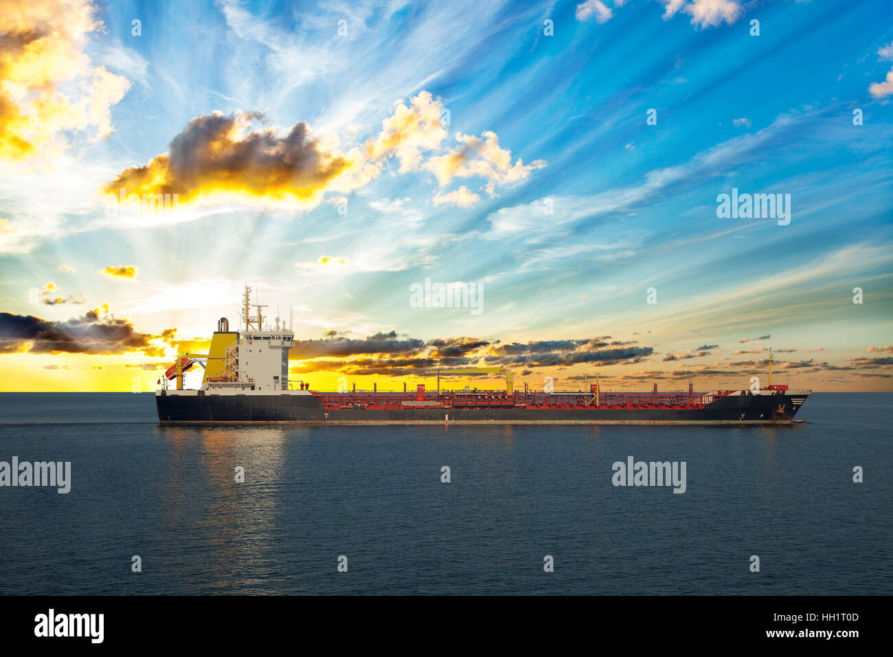 Sun setting at the sea with tanker ship Stock Photo - Alamy