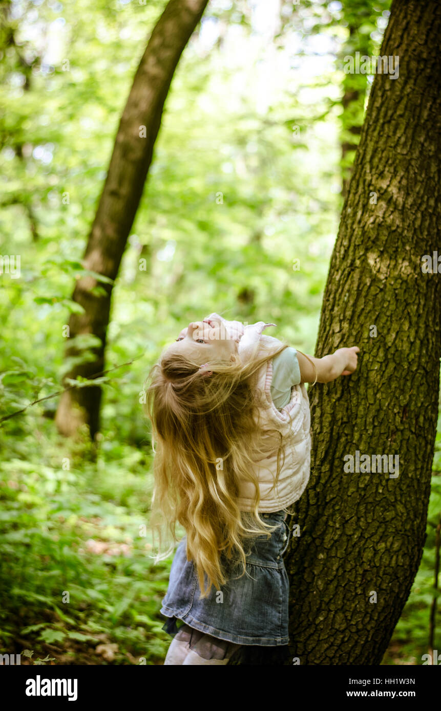 girl with long hair hanging in tree trunk in green spring forest Stock ...