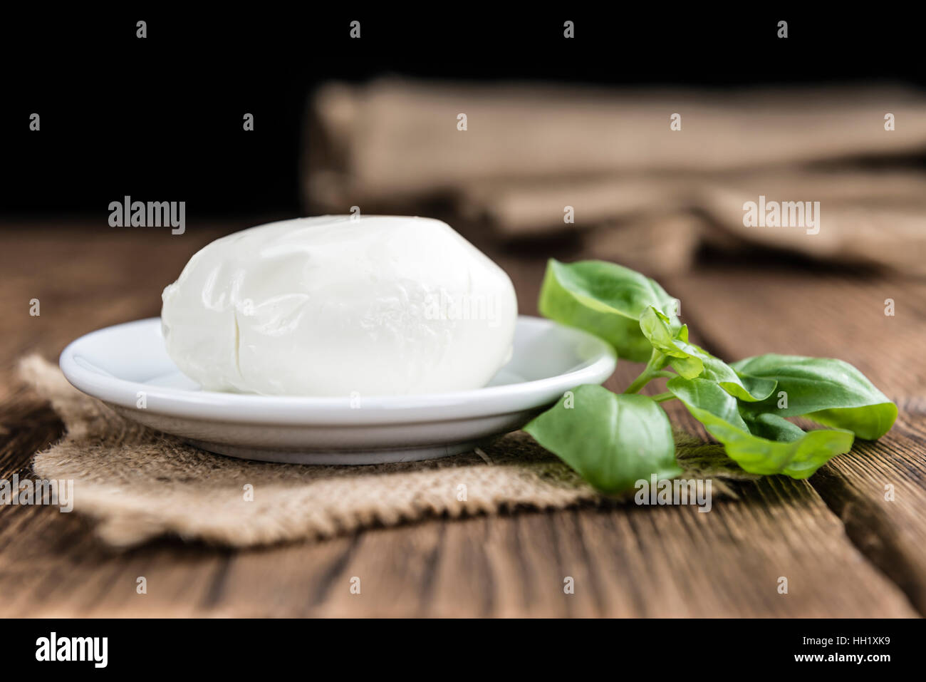 Portion of fresh Mozzarella (close-up shot) on wooden background ...