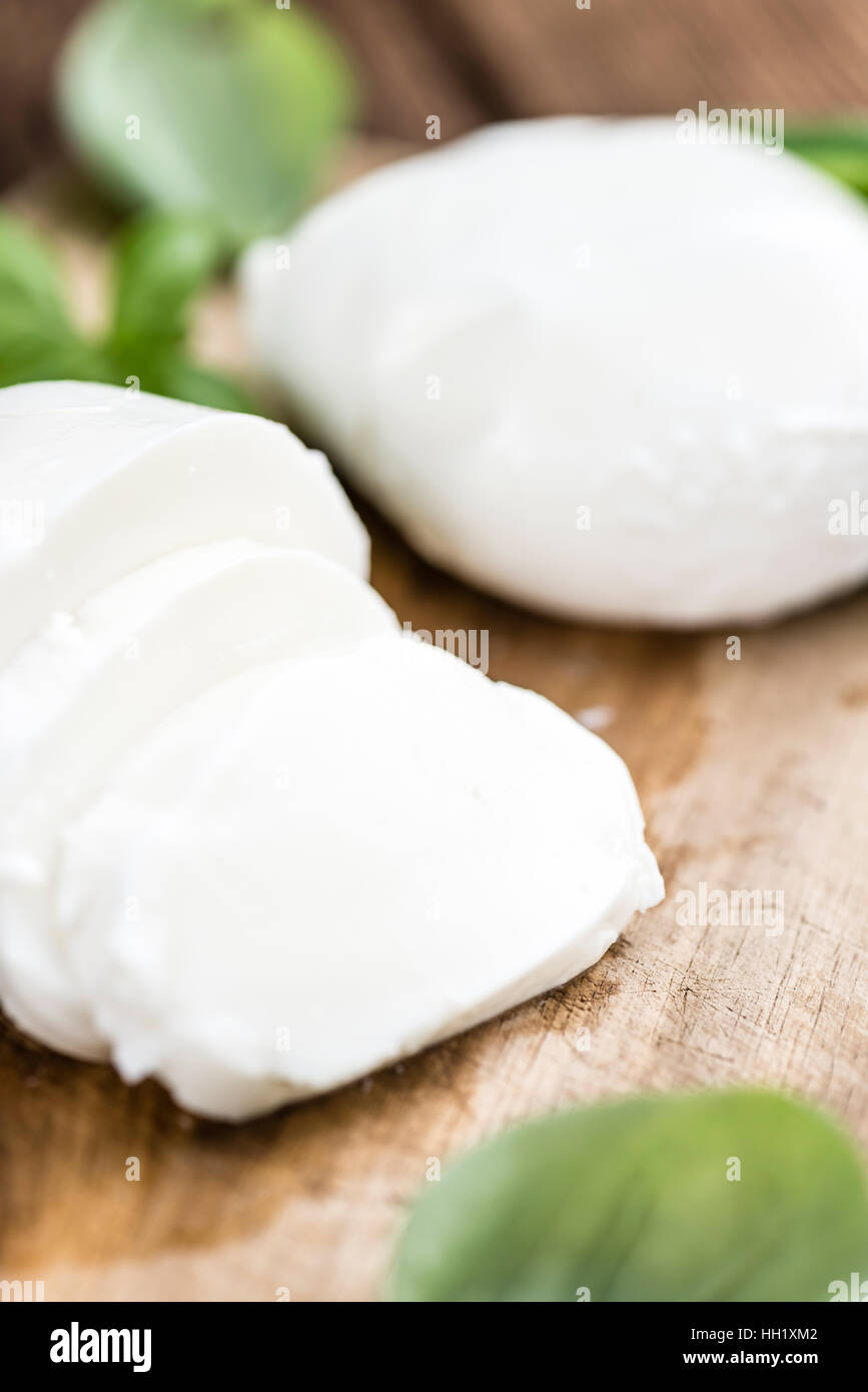 Portion of fresh Mozzarella (close-up shot) on wooden background ...