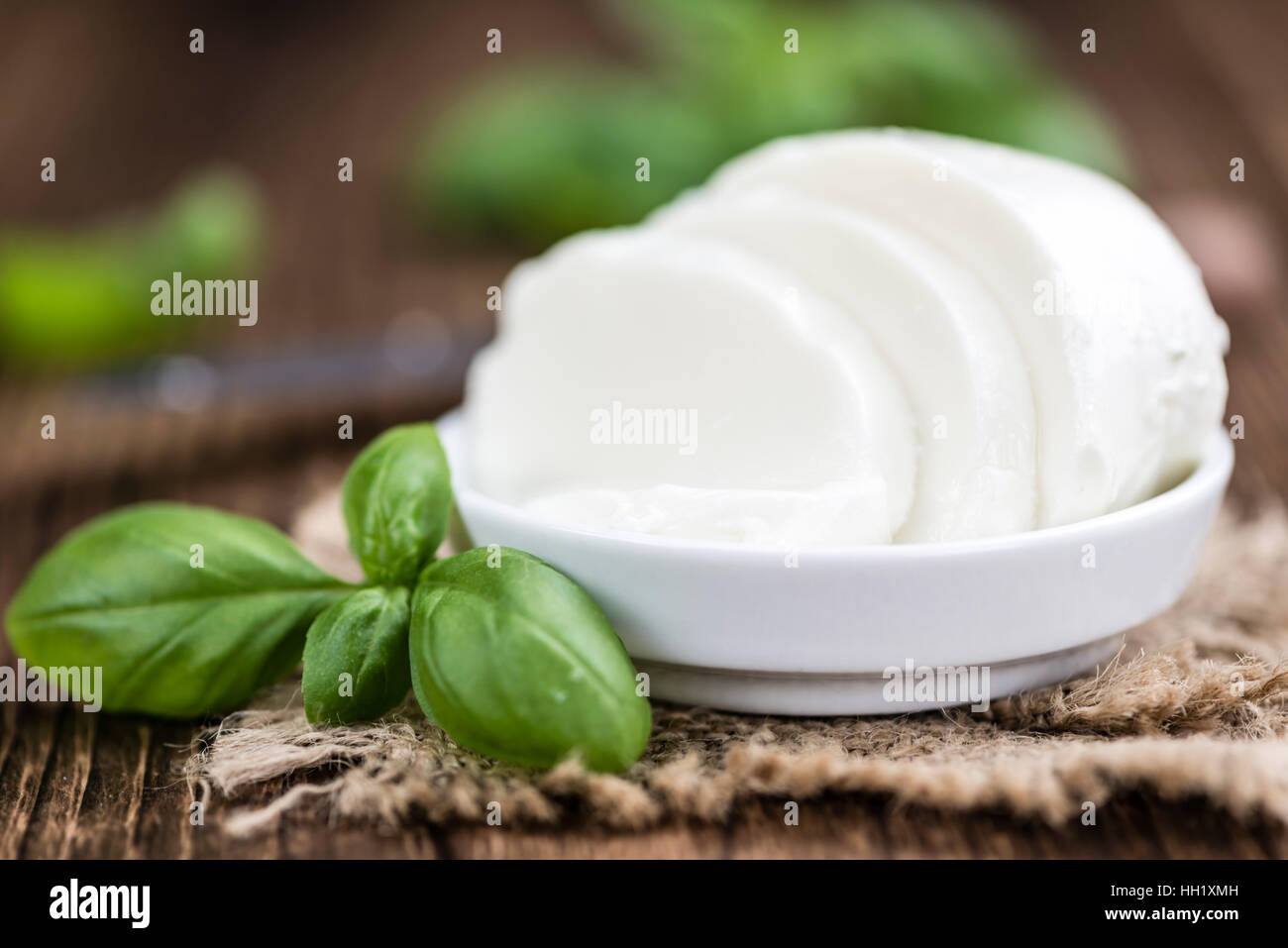 Portion of fresh Mozzarella (close-up shot) on wooden background ...