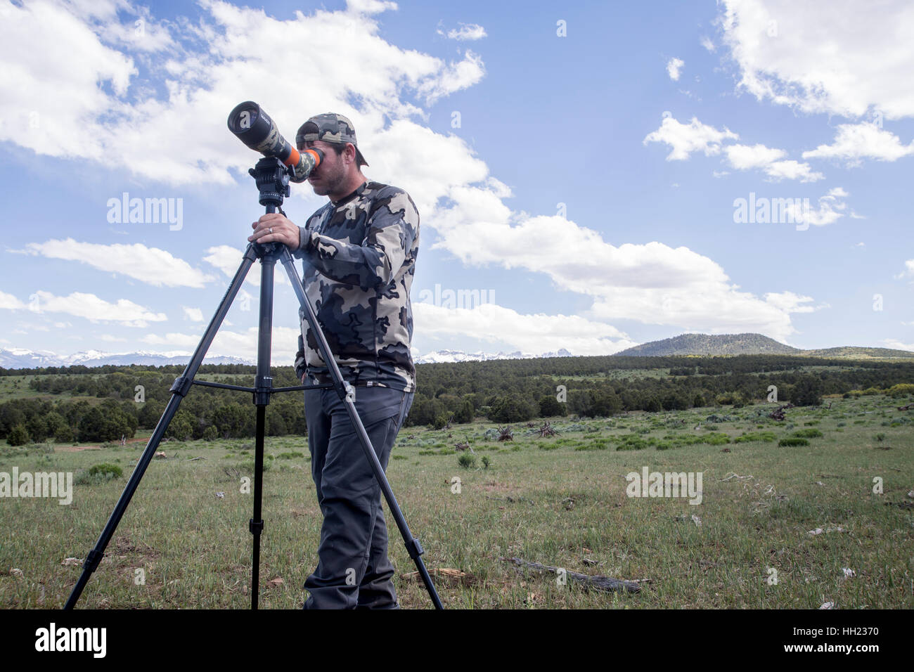 Male in camo looking through a spotting scope in the Colorado outdoors ...