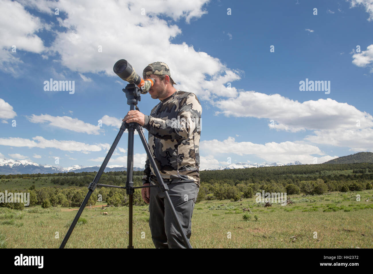 Male in camo looking through a spotting scope in the Colorado outdoors ...