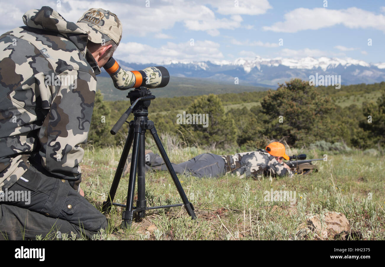 One hunter shooting while the other watches through a spotting scope in ...