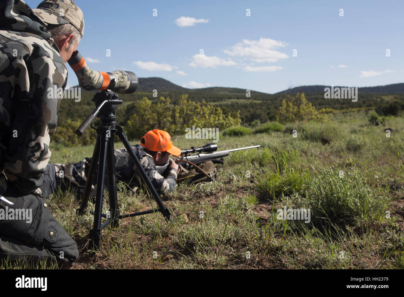 One hunter shooting while the other watches through a spotting scope in ...
