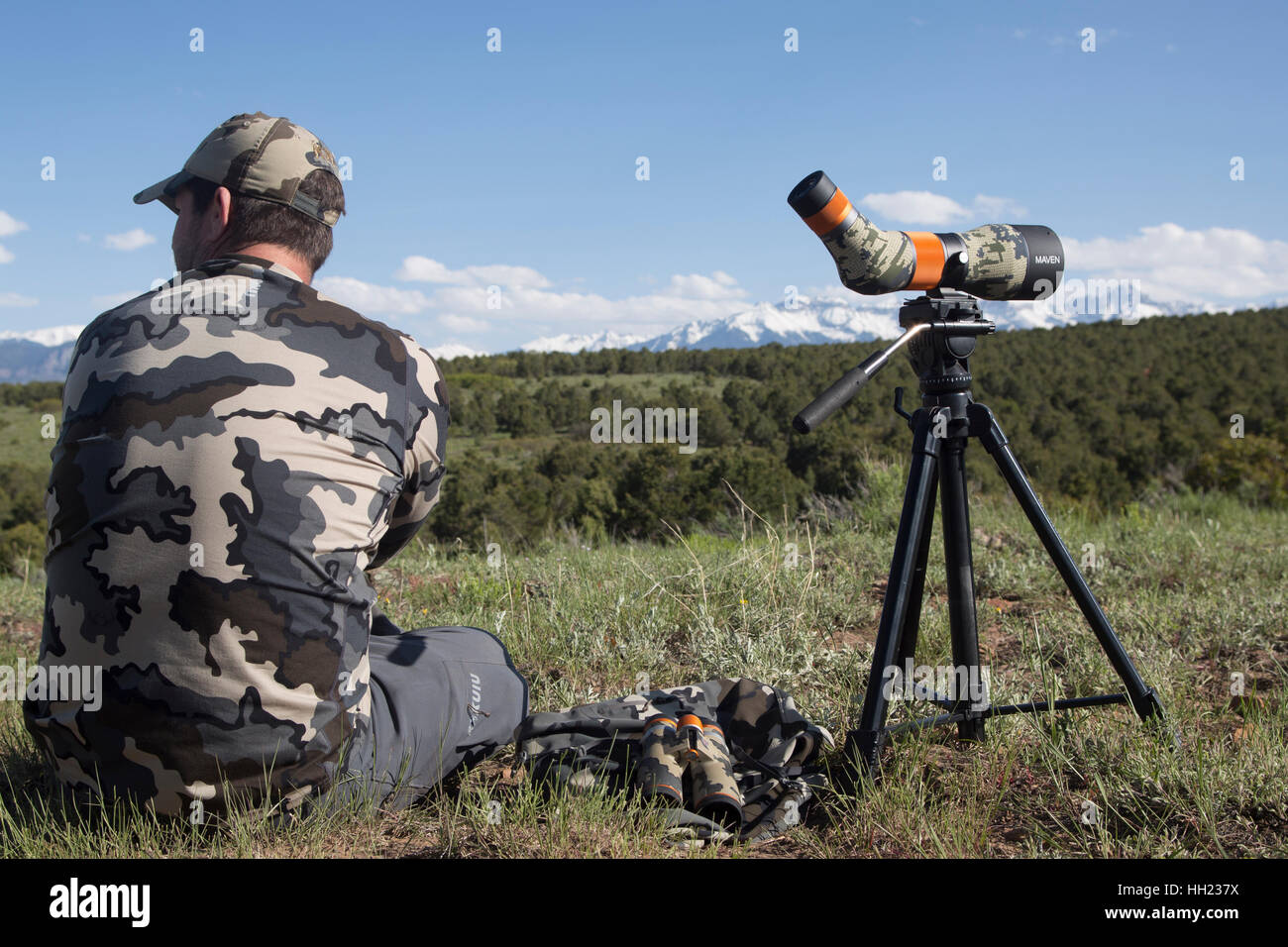 Outdoors man sitting near his spotting scope looking at the country ...
