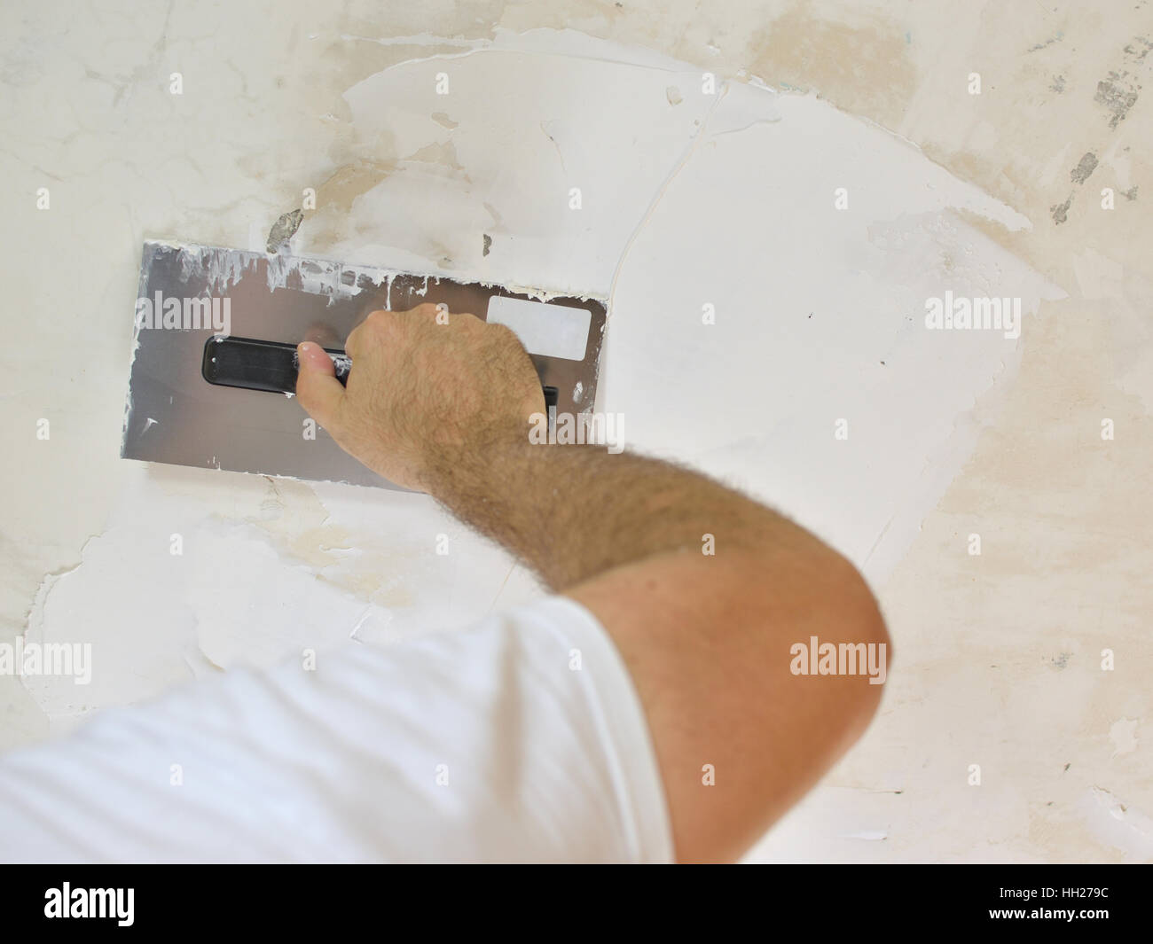 Spreading spackling compound with a finishing trowel to a ceiling Stock ...