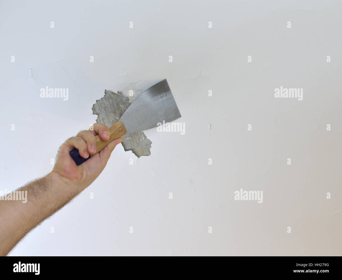 Hand holding a plaster spatula, scraping a ceiling, preparing it for ...