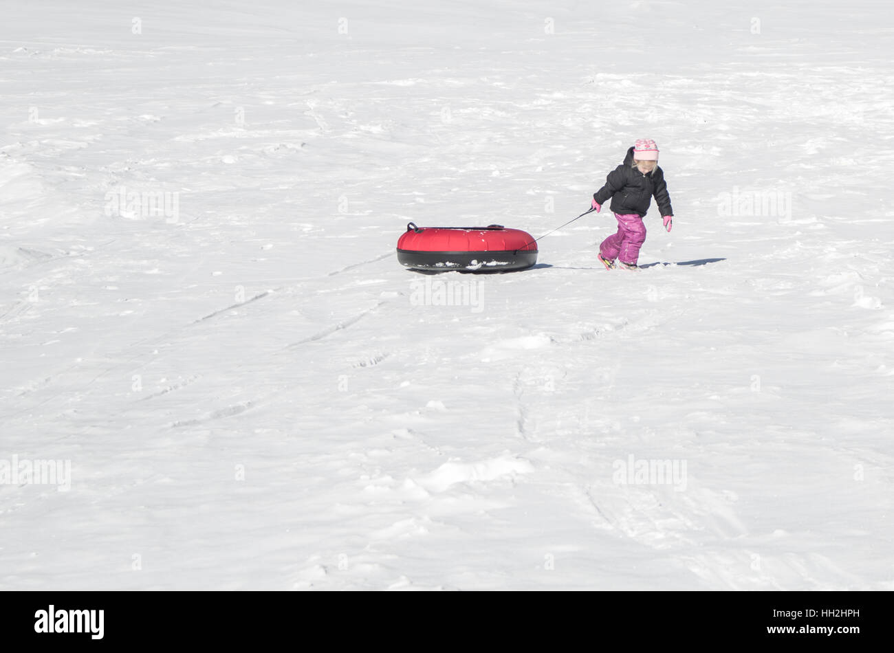 Young child pulling a sled up the snowy hill Stock Photo - Alamy