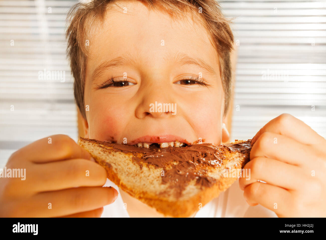 Happy kid boy eating toast with chocolate spread Stock Photo - Alamy