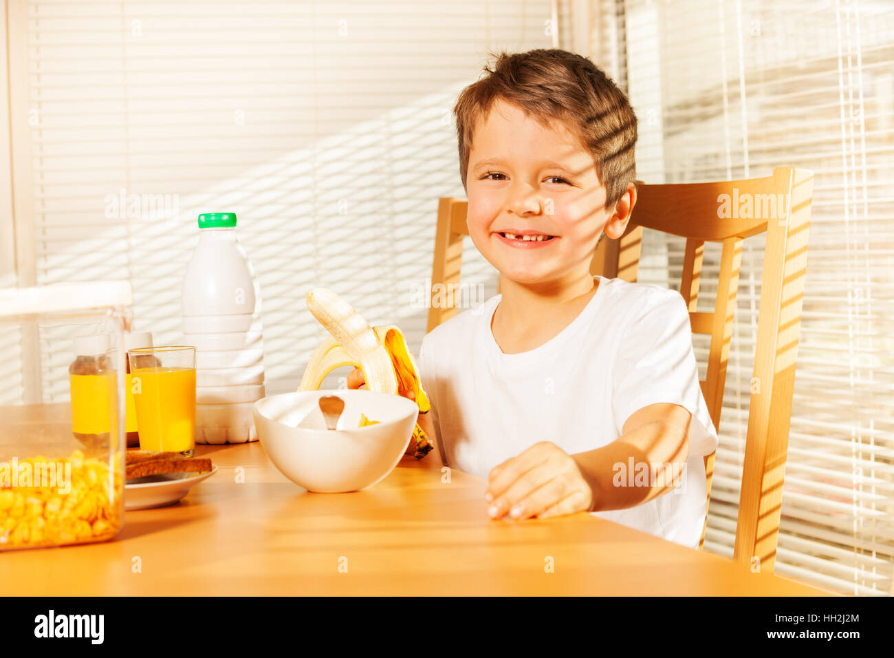 Smiling kid boy holding banana in the kitchen Stock Photo - Alamy