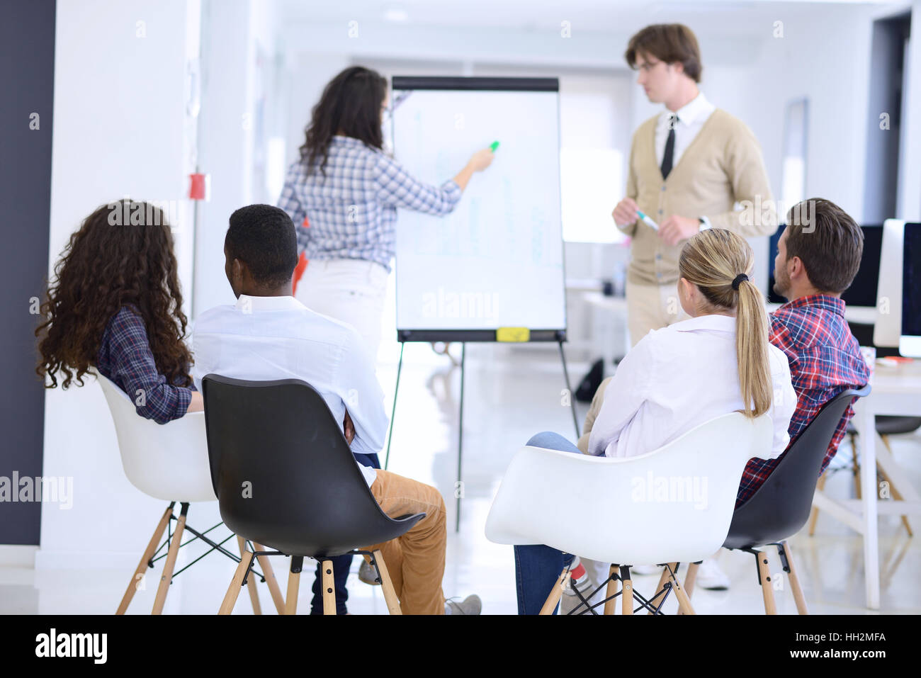 Businessman giving a presentation to his colleagues at work standing in ...