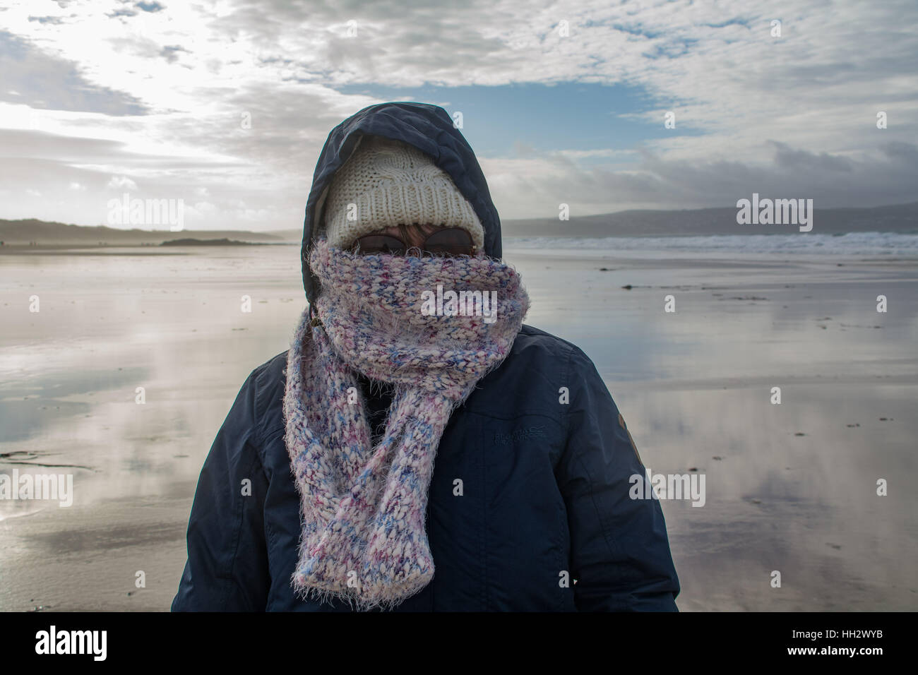Woman well wrapped up on windy beach with scarf, hat, hood Stock Photo ...
