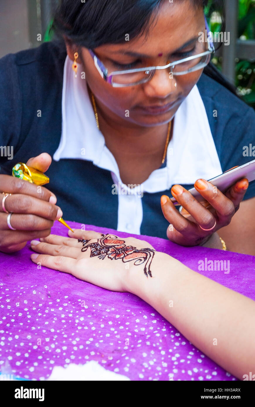 GEORGE TOWN, MALAYSIA - OCTOBER 25: Woman drawing a henna tattoo on a ...
