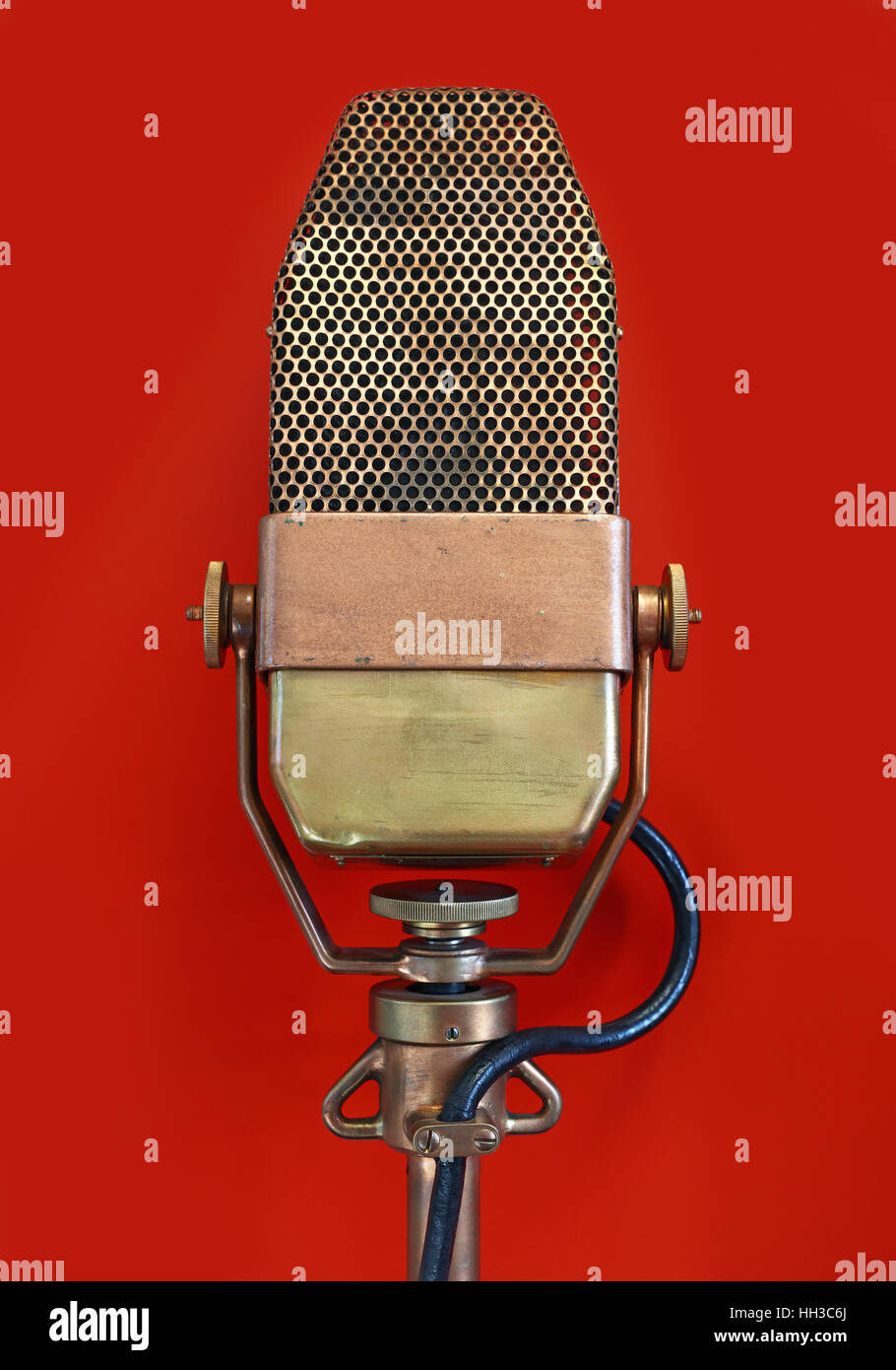 Vintage old retro vocal metal microphone side view close up over red ...