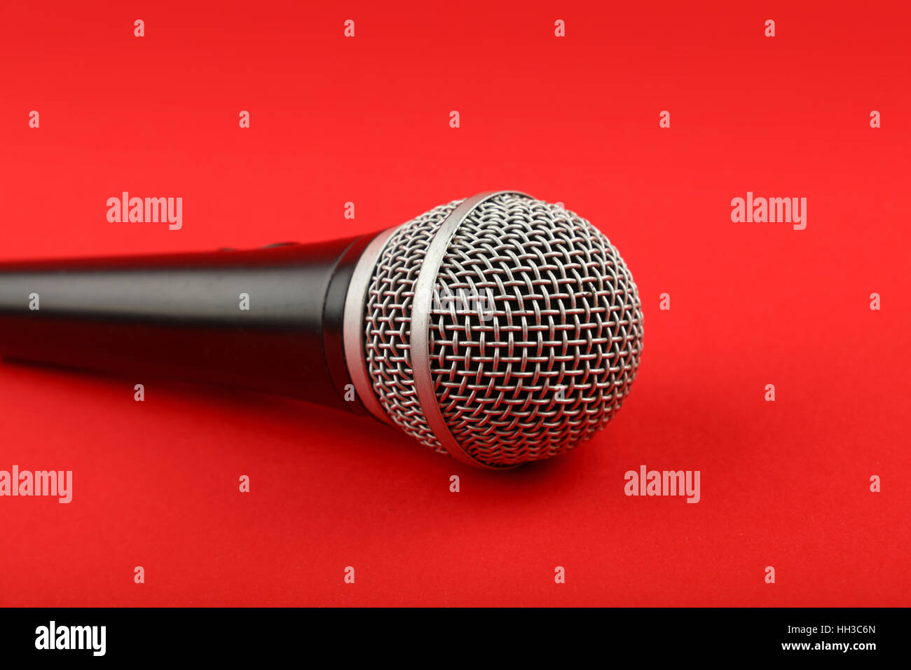 Black and silver vocal microphone side view close up on red background ...