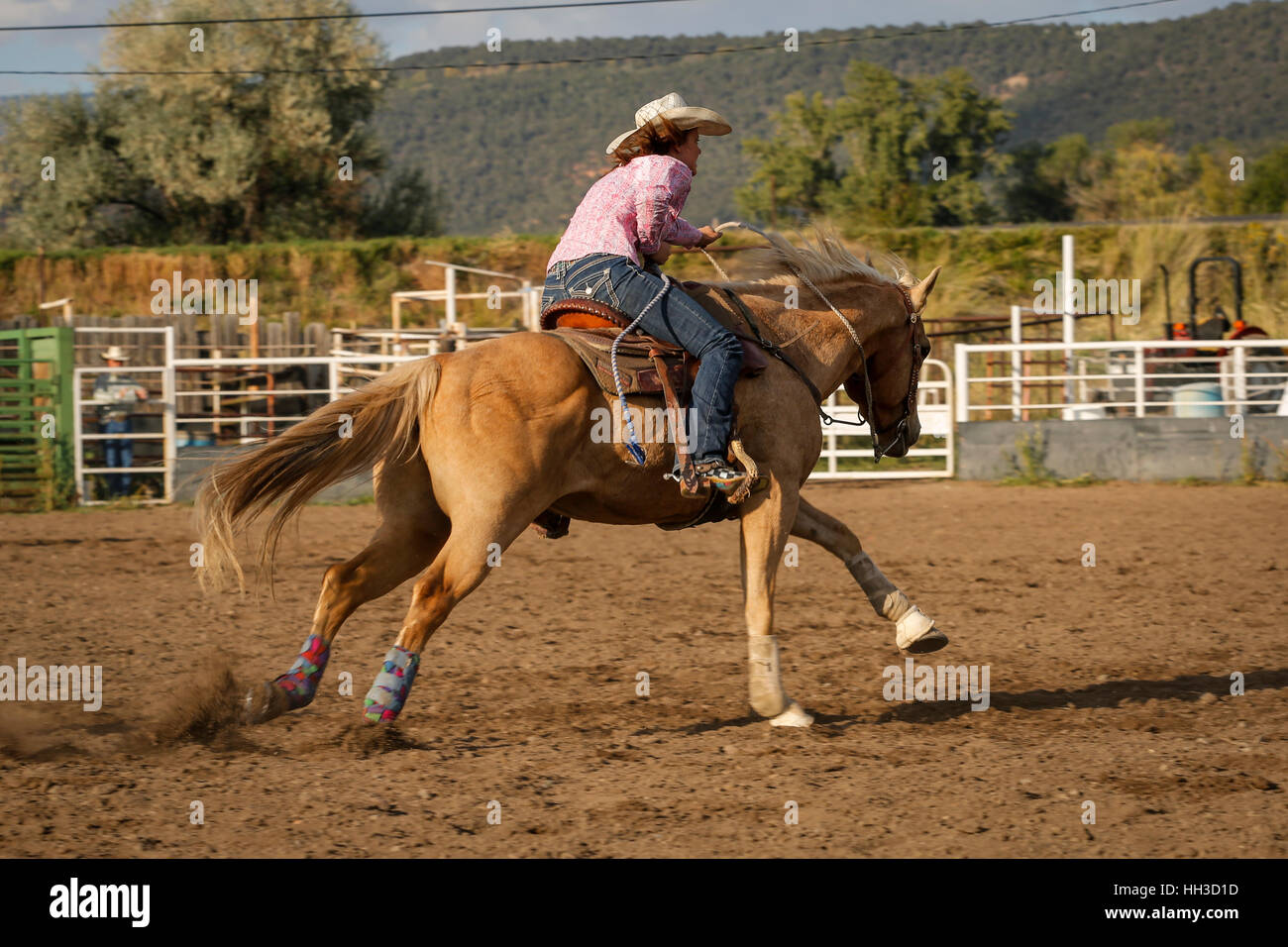 Young woman riding a horse through a rodeo arena during a youth rodeo ...